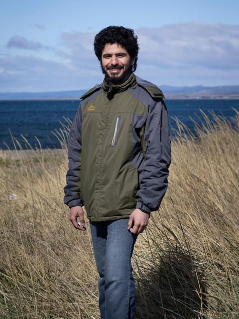 Adrián Simancas, 24, in Punta Arenas in Chile. Er steht in olivgrüner Jacke am Meer